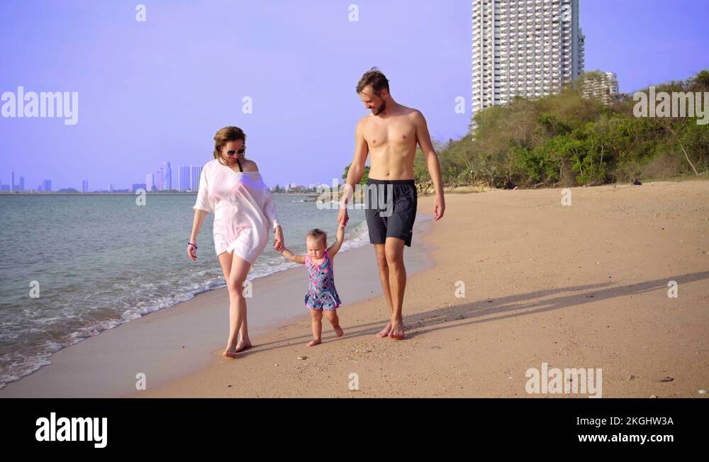 Happy family at the beach, holding hands, waving a little girl around ...