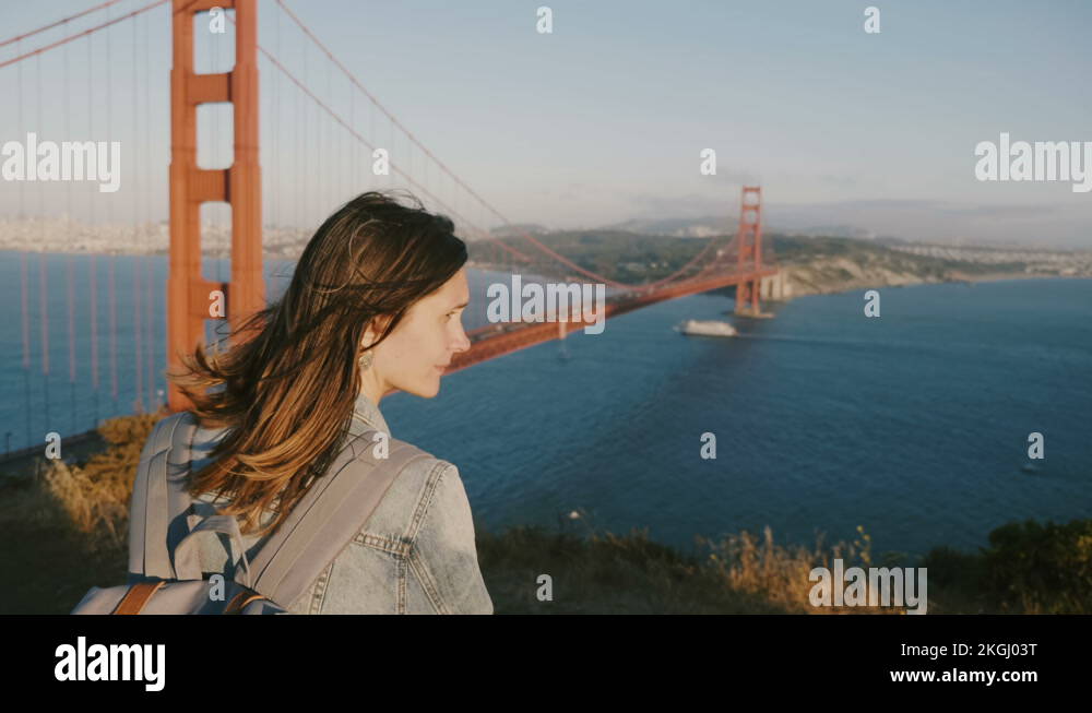 Beautiful back view of young tourist woman with backpack, hair blowing ...