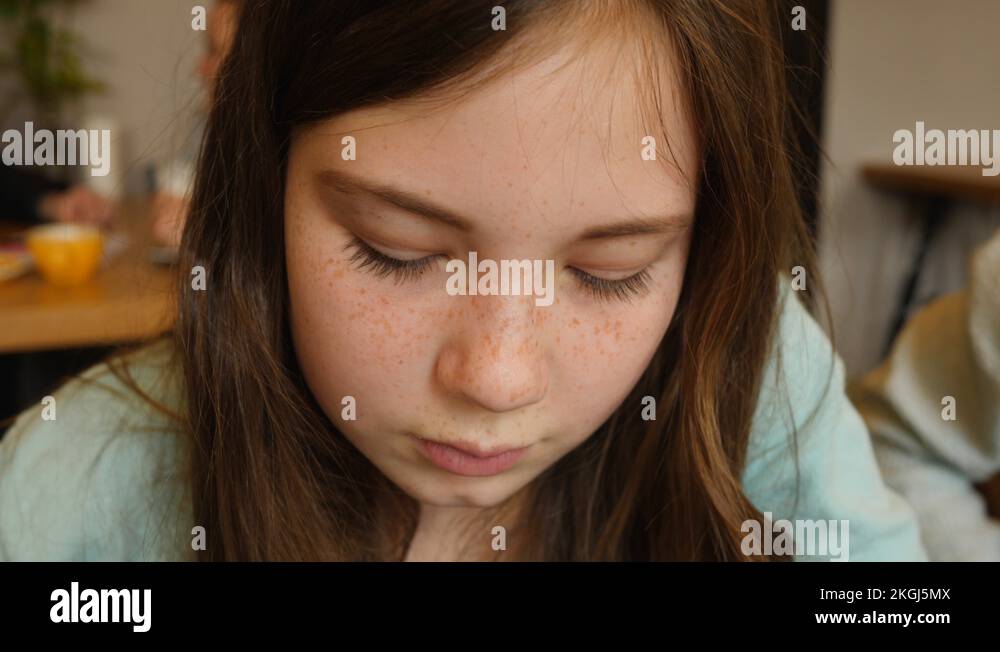 Closeup cute kid girl face portrait while eating piece of cake in a ...