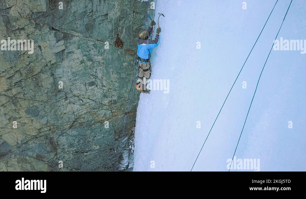 Alpinist with axes is training climbing skills on frozen waterfall ...