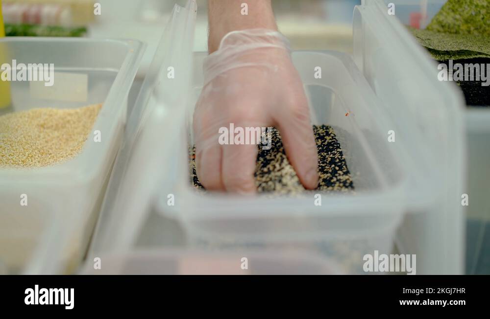 Cook takes the workpiece for the Japanese roll from the sesame ...