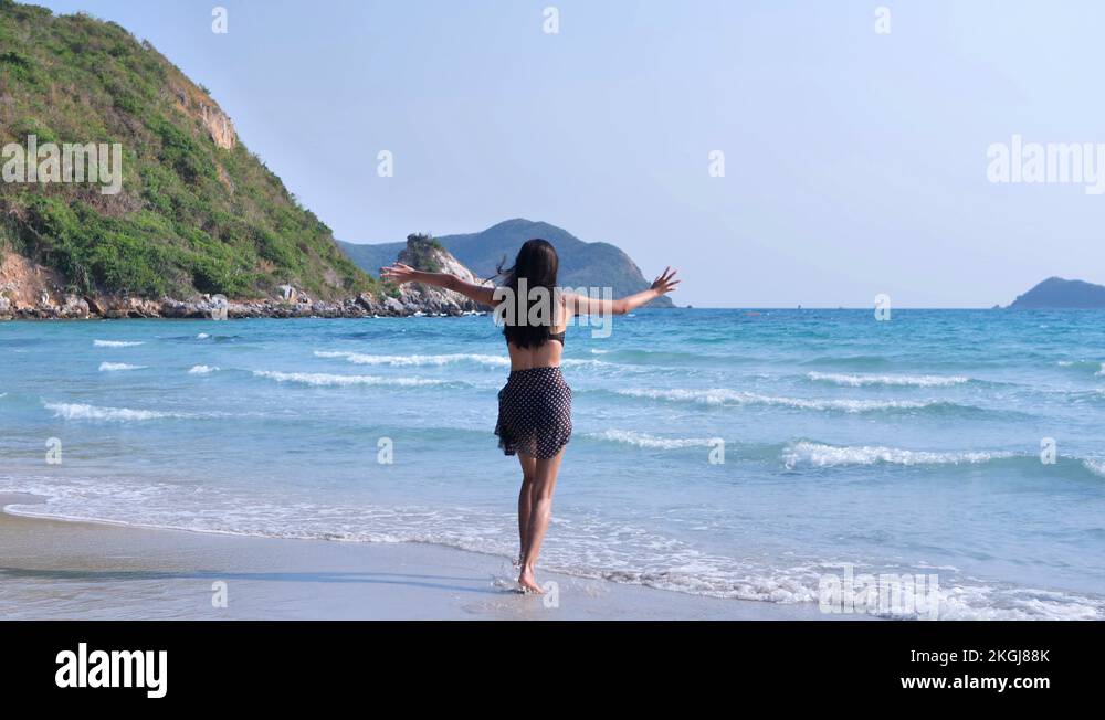 Beautiful young Asian woman in a bikini enjoying a running to the sea ...