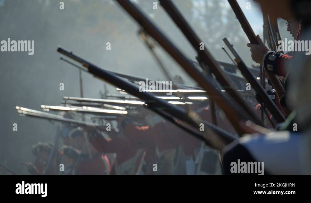 British Redcoat re-enactors on battlefield fire black powder musket ...