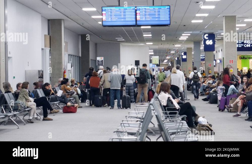 Passengers patiently queue and sit near departure gate within Galeao ...