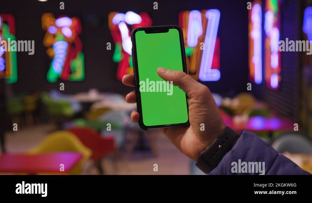 Male hand holding mobile phone, touching green screen. Young man in ...