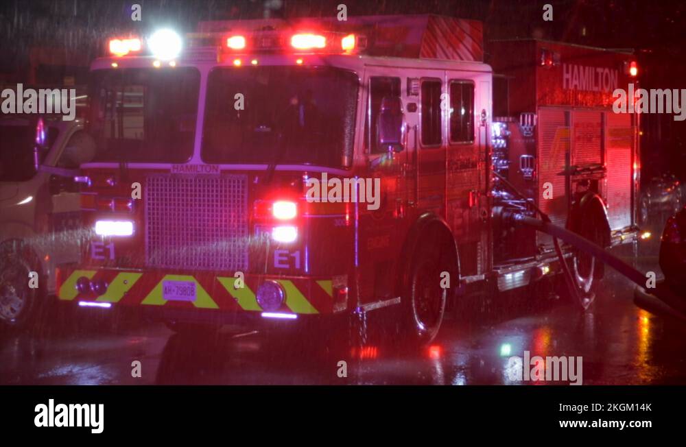 Fire engine in the rain with flashing emergency lights. Red and white ...