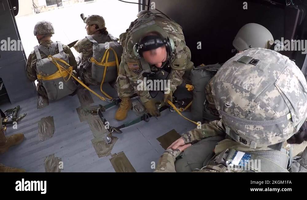 U.S. Army jumpmaster attaches paratroopers static line to UH-60 Black ...