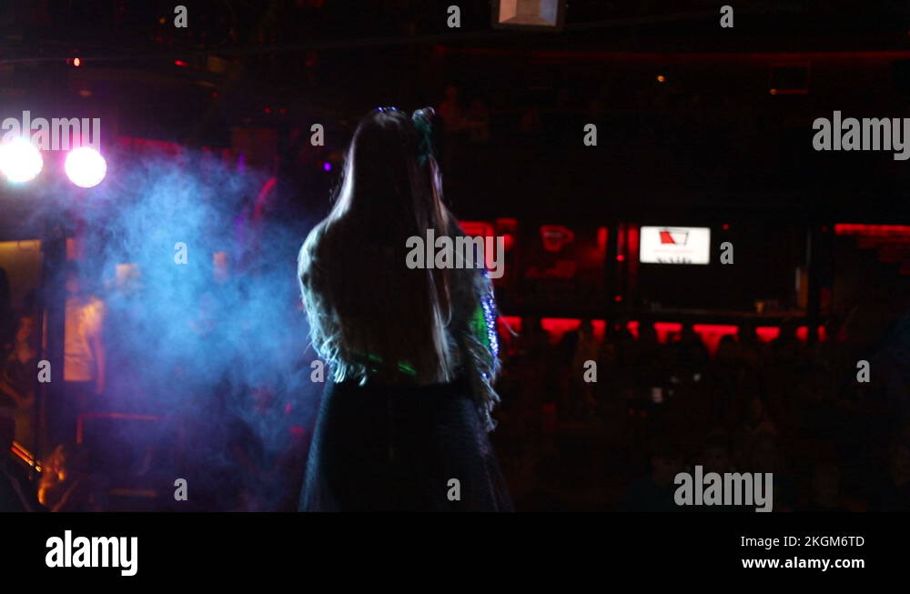 Girl who sings and dances on stage, Back view of singer. Light and ...