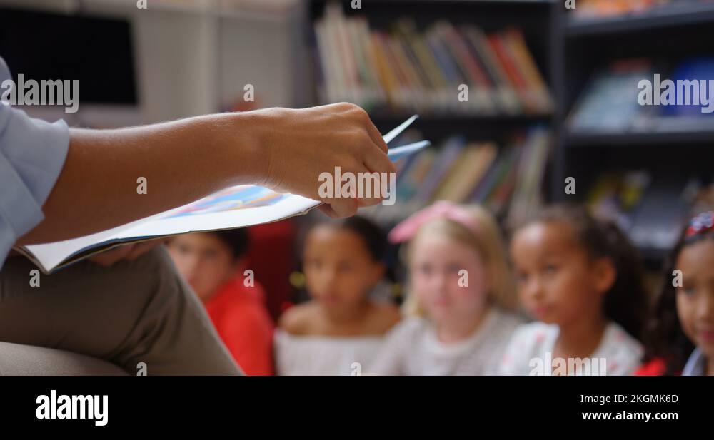 Mid section of female teacher teaching schoolkids in the school library ...