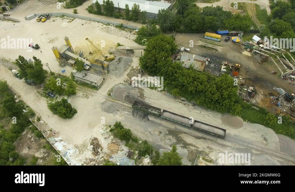 old concrete factory with conveyor, storage towers and cargo train ...