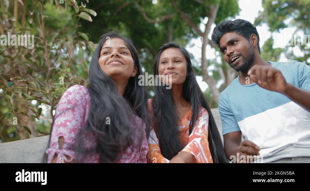 Three Young South Asian friends, one guy and two girls are cute talking ...