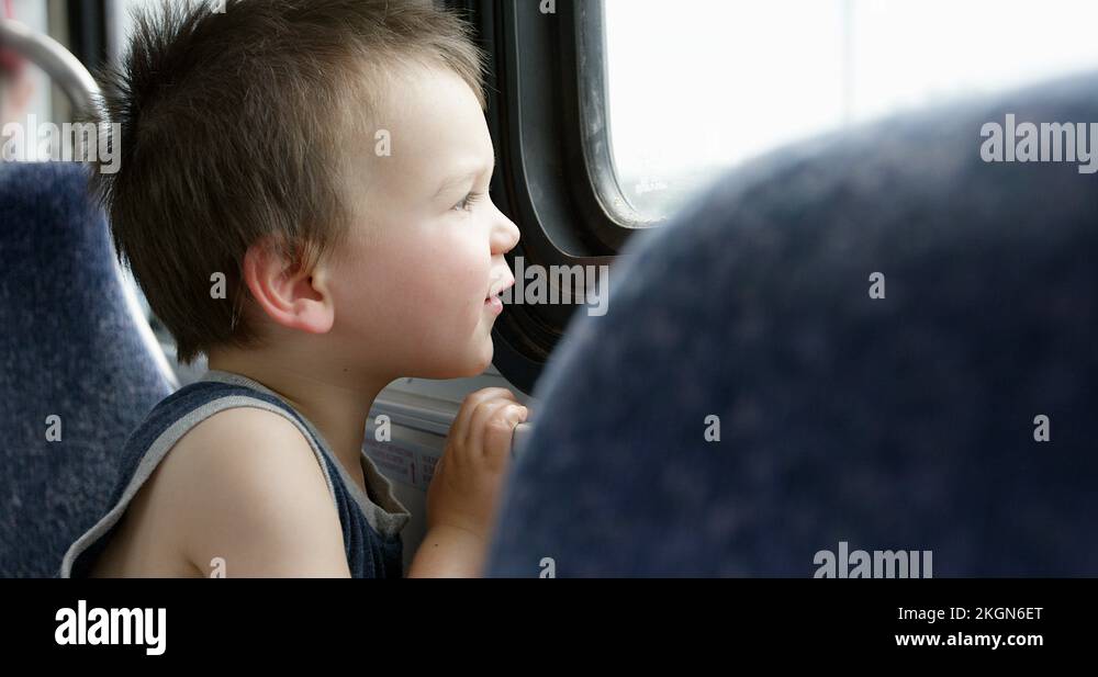 Toddler boy looking out window of public city bus - young and happy ...