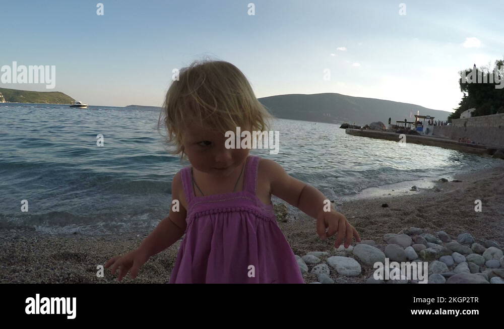 Cute kid walks on the beach, little girl is walking on seaside evening ...