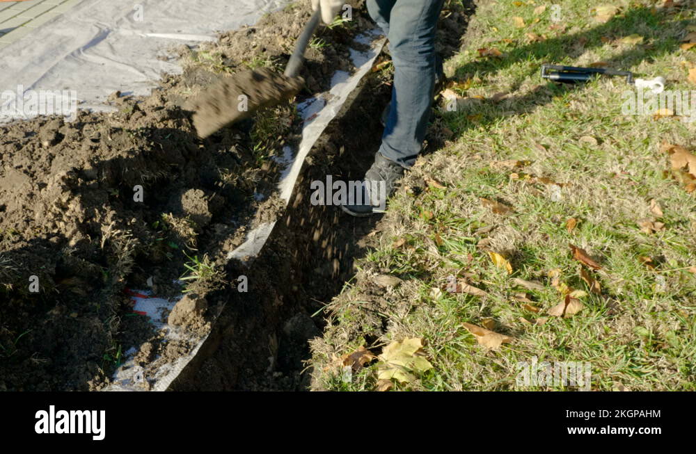 Man digging a trench using shovel to make automatic watering in the ...