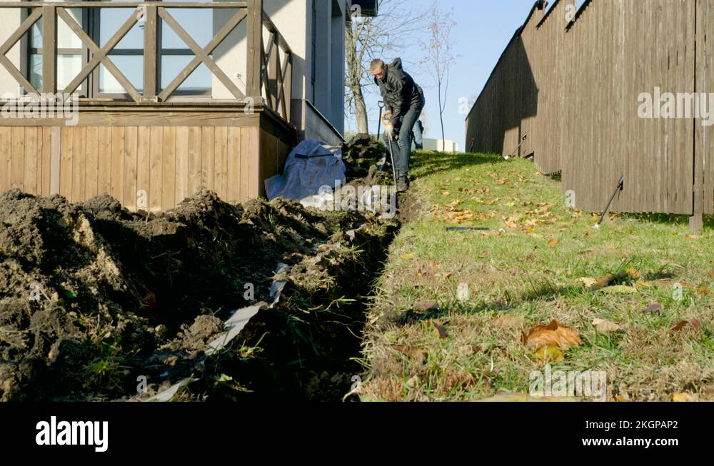 Two men digging a trench using shovels to make automatic watering of ...