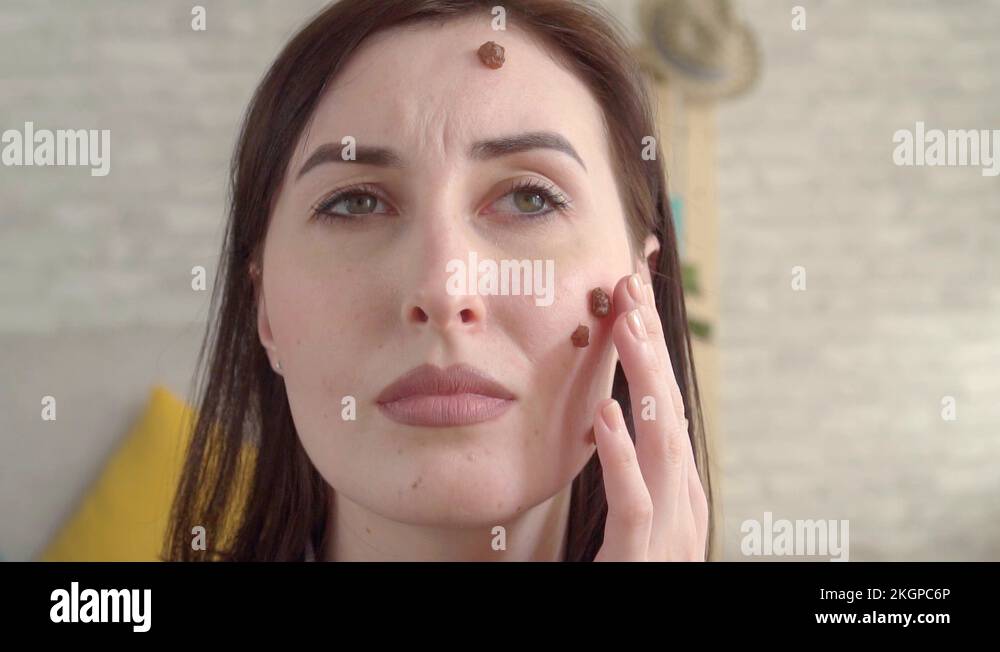 Young sad woman with moles on her face looking in the mirror slow mo ...