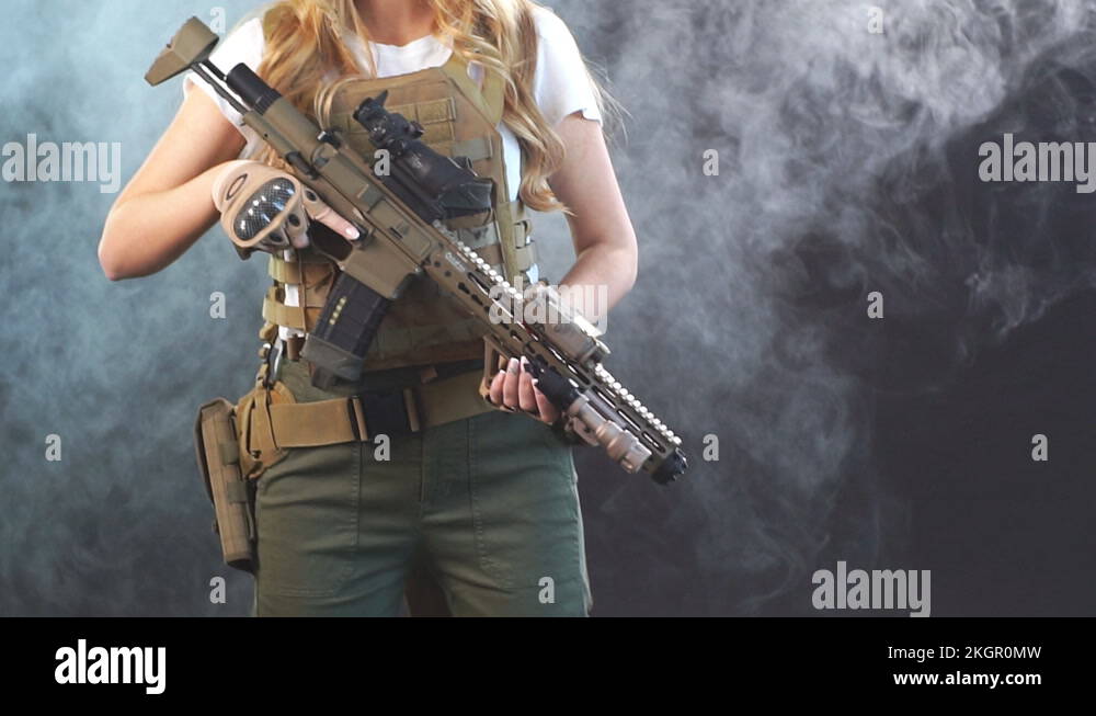 Cute sniper woman with rifle in hands standing in military outfit in darkness Stock Video ...