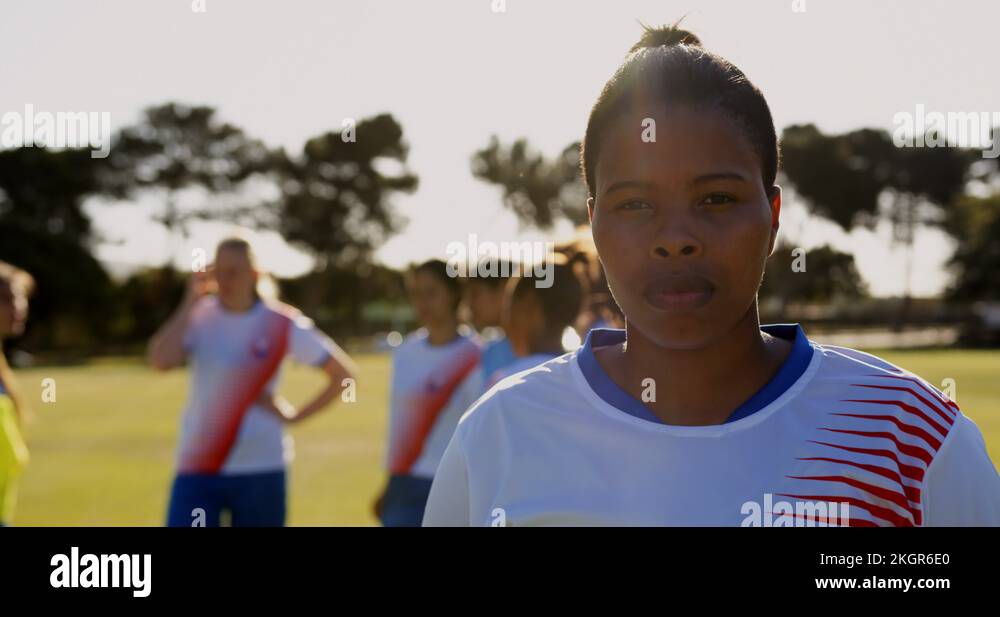 Female soccer player standing while teammates talk on soccer field. 4k ...