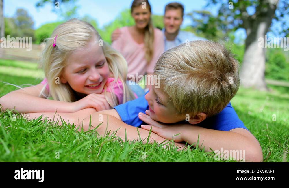 Brother And Sister Tickling Each Other While Lying In The Grass Stock