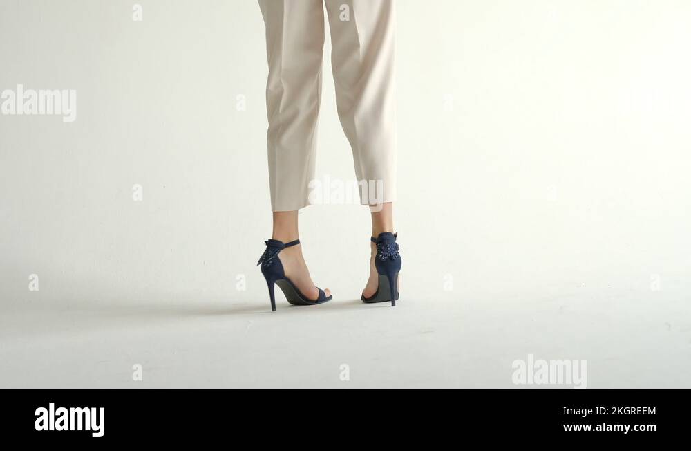 Tracking with low-section of silhouette of female legs in high heels ...