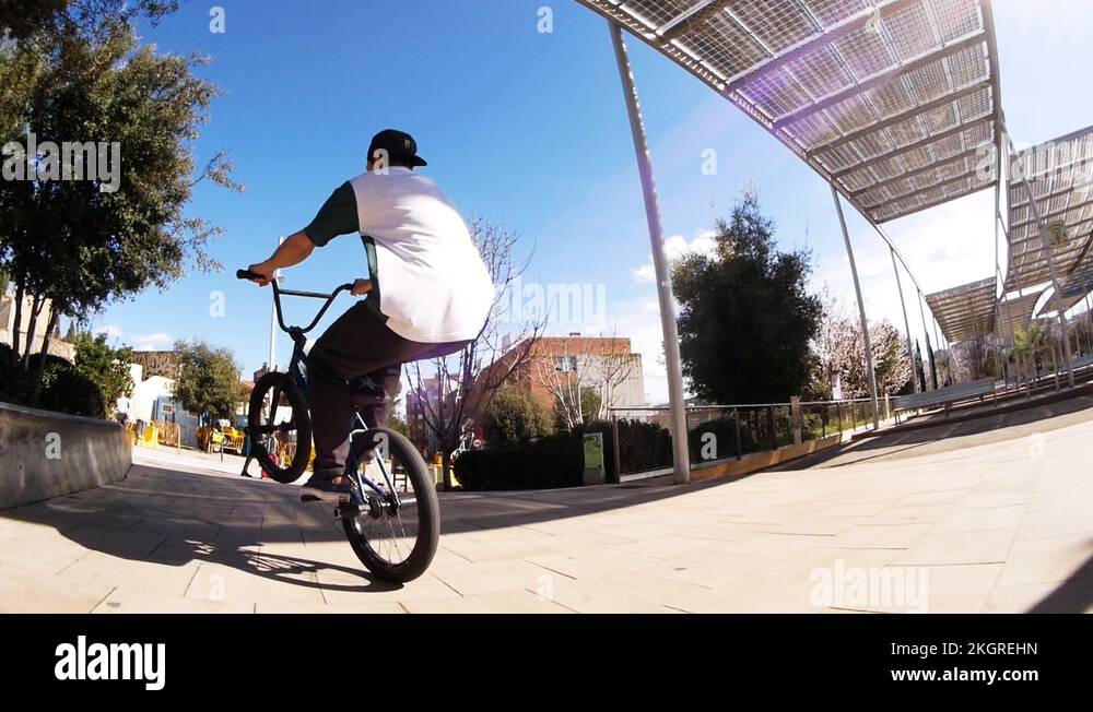Active guy bmx rider is riding in street on pathway and jumping on wall ...