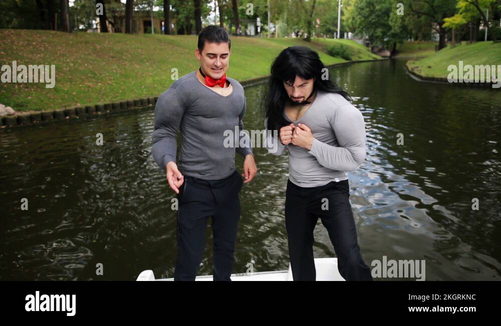 Two attractive guys dressed in fake muscle padded costumes dance in ...
