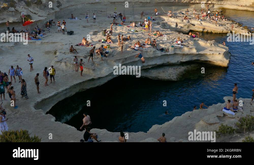 Crowd of people in a beach standing on rock cliffs watching cliff ...