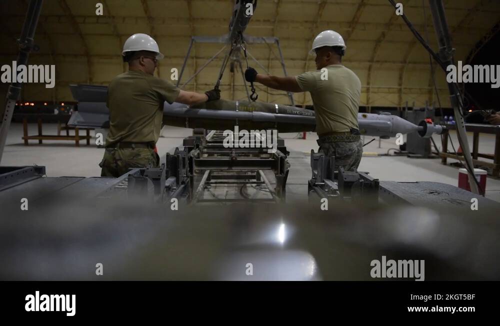 U.S. airmen lifting ordnance with hoist inside hangar at Al Dhafra Air ...