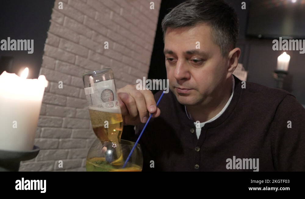 Drunk man continues to drink a cocktail. Loneliness and booze. Bachelor ...