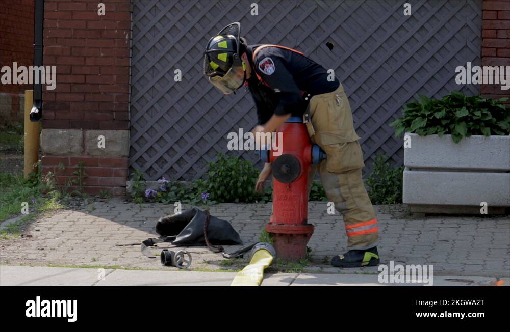 Fireman assembles a fire hydrant during a structure fire in the day ...