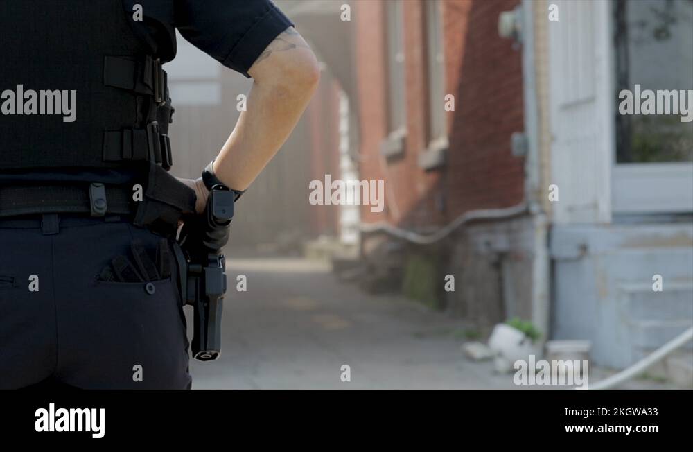 Police office standing with hand on gun. Serve and protect concept ...