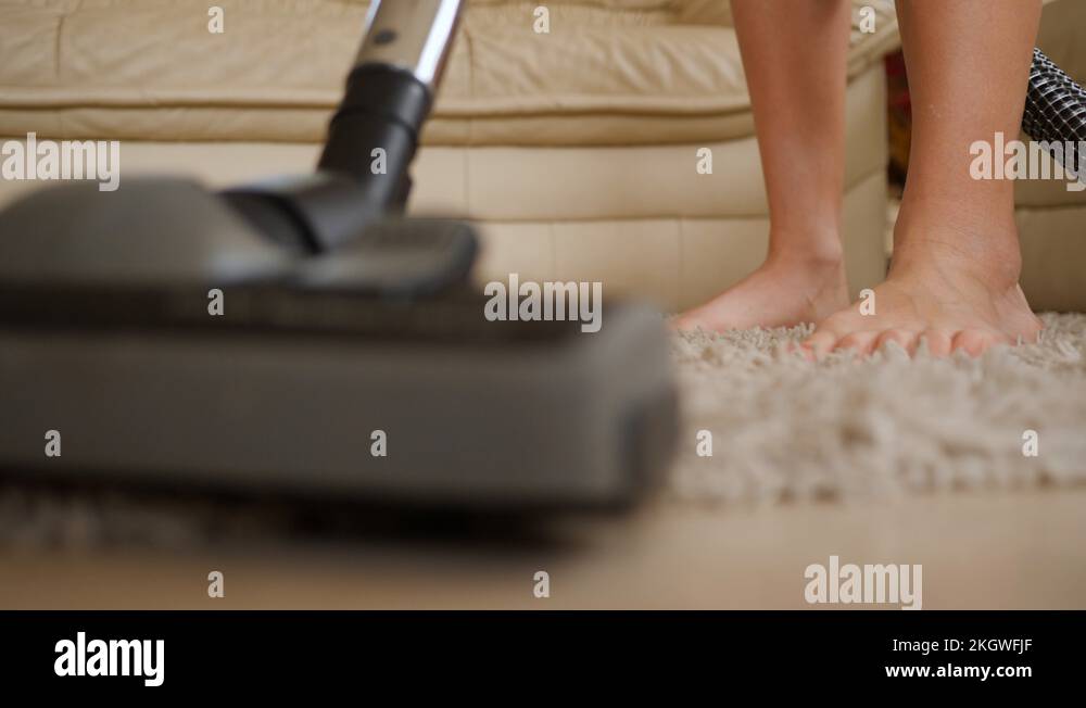 Teenager girl daughter barefoot legs during vacuuming cleaning the ...