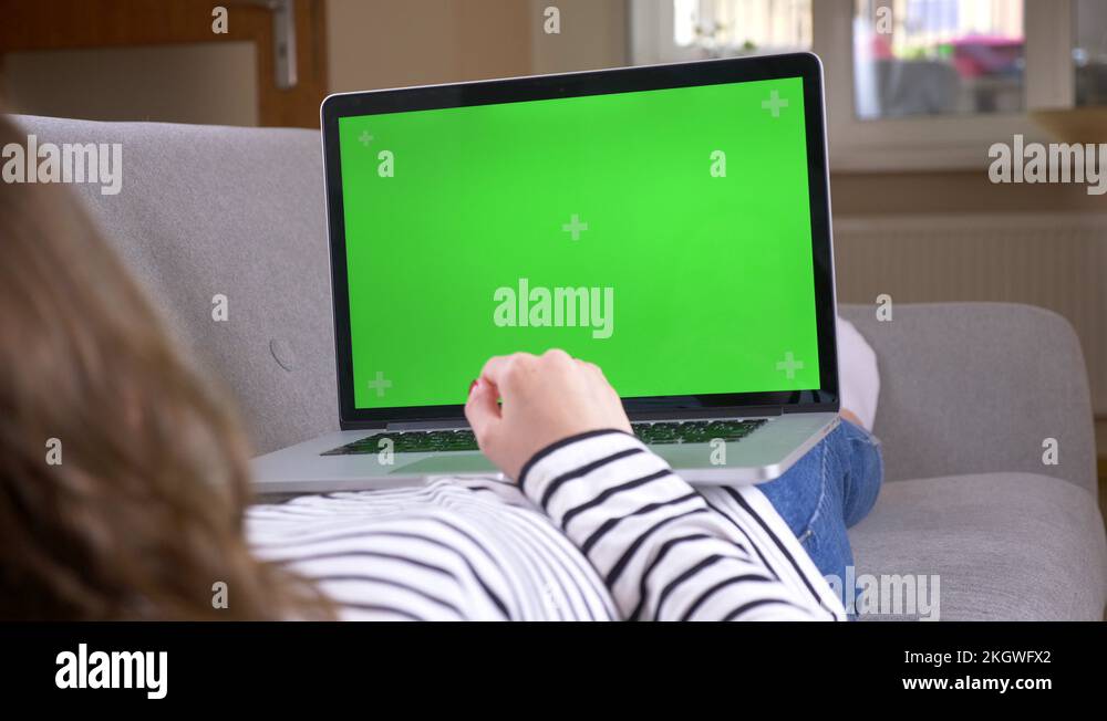 Closeup back view shoot of female typing on the laptop with green ...