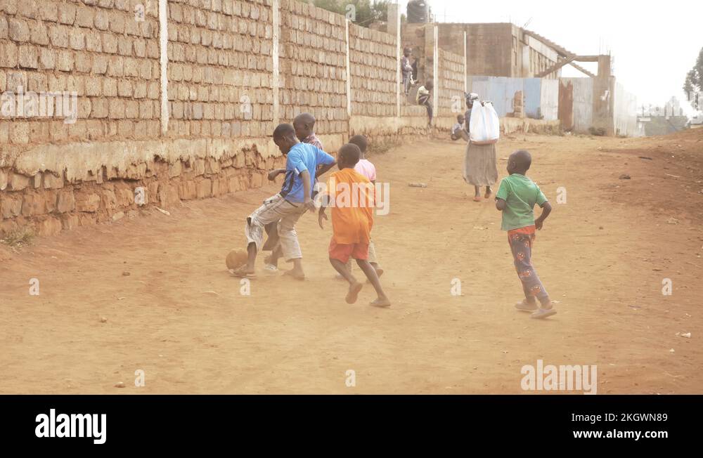 African children playing on the streets with a deflated football in the ...