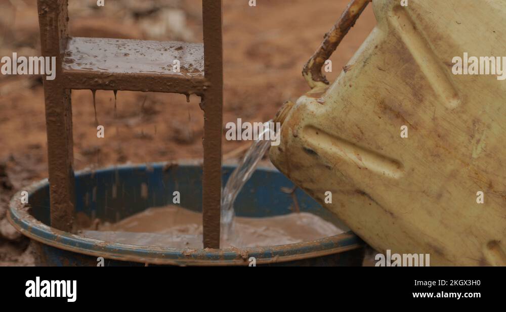 Women make Bricks, pressing mud mixture into an open timber frame ...