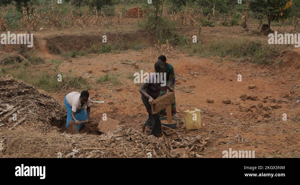 Women make Bricks, pressing mud mixture into an open timber frame ...