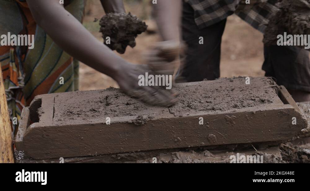 Women make Bricks, pressing mud mixture into an open timber frame ...