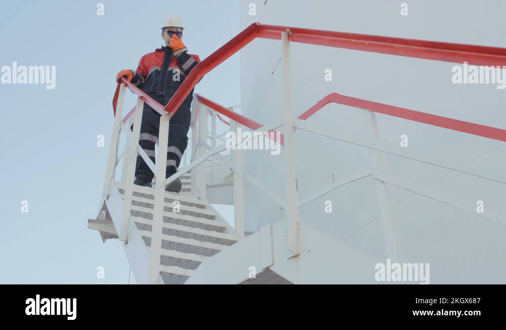 Petrochemical engineer goes down metal ladder of huge fuel tank and ...
