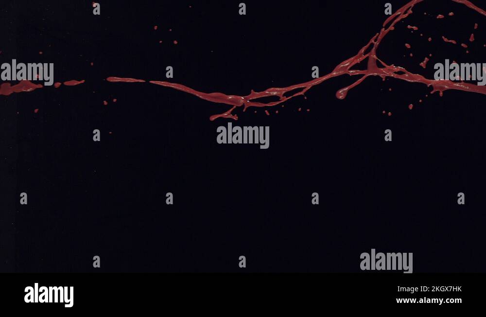 Thin stream of red fluid splashing and pouring across screen in slow ...