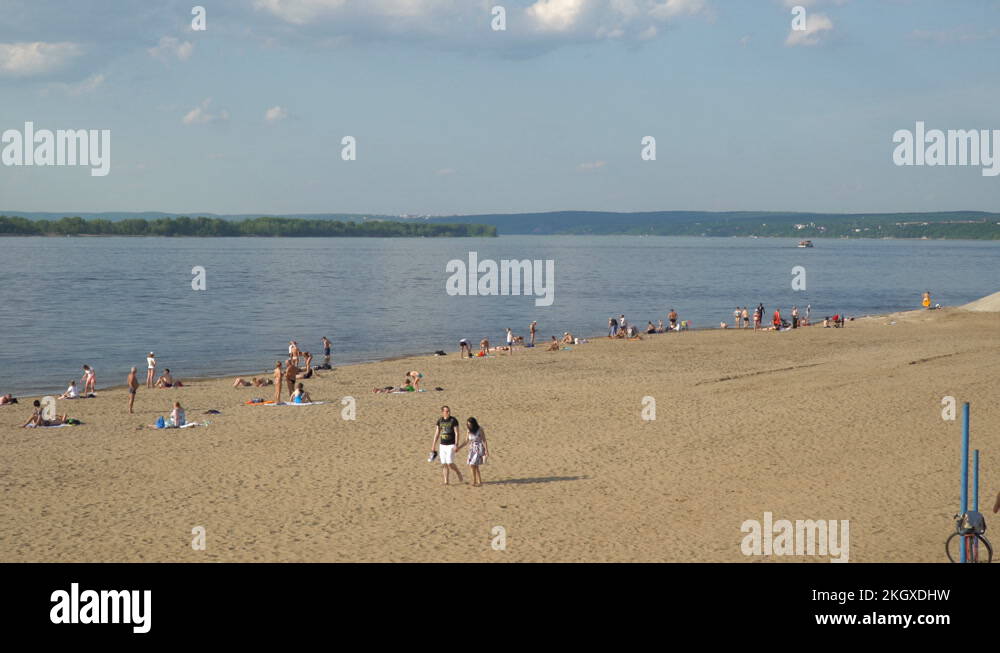 People swim and sunbathe on the beach of the Volga river embankment ...