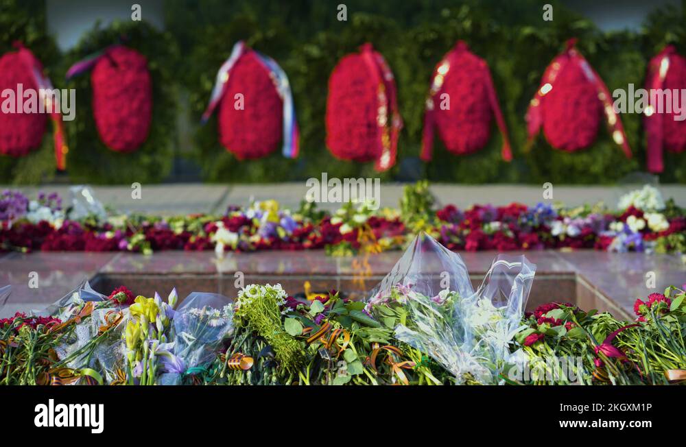Green funeral flowers on the Eternal Flame. Fire burn in memory of ...