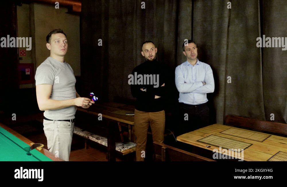 Men playing in game of darts, throwing a dart arrow in center of ...