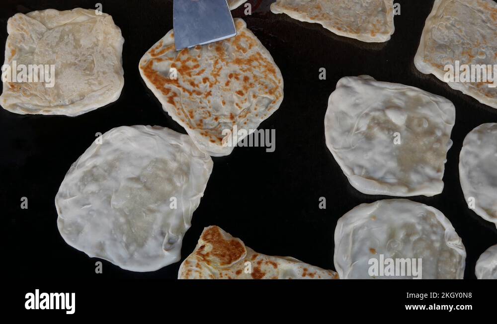 Chef making a lot of traditional Indian food called 'Roti Canai'. 4k ...