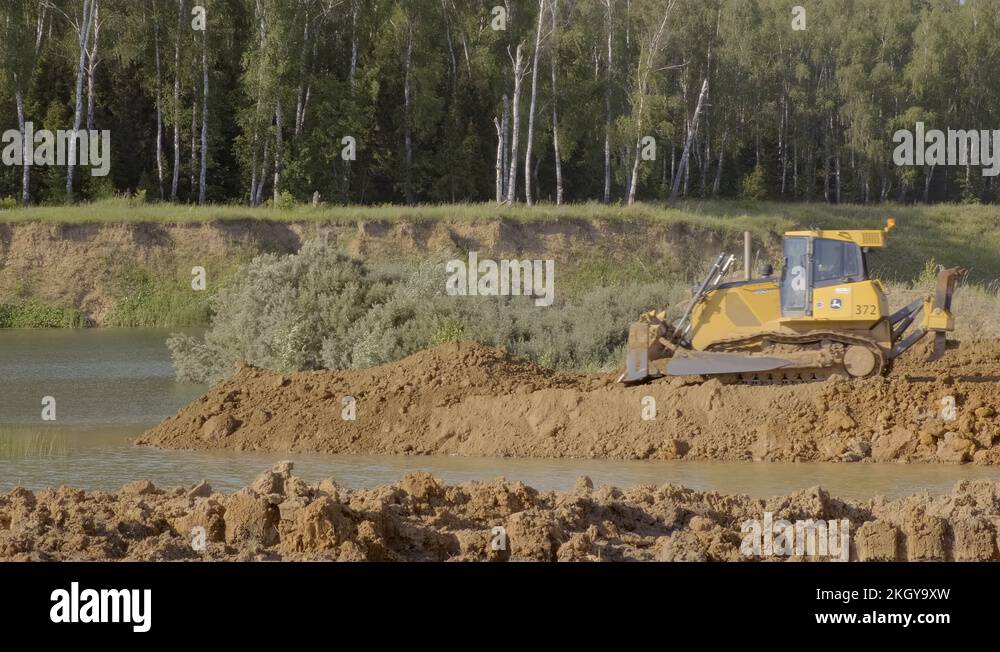 crawler tractor bucket leveling pile of clay dumping into water Stock ...
