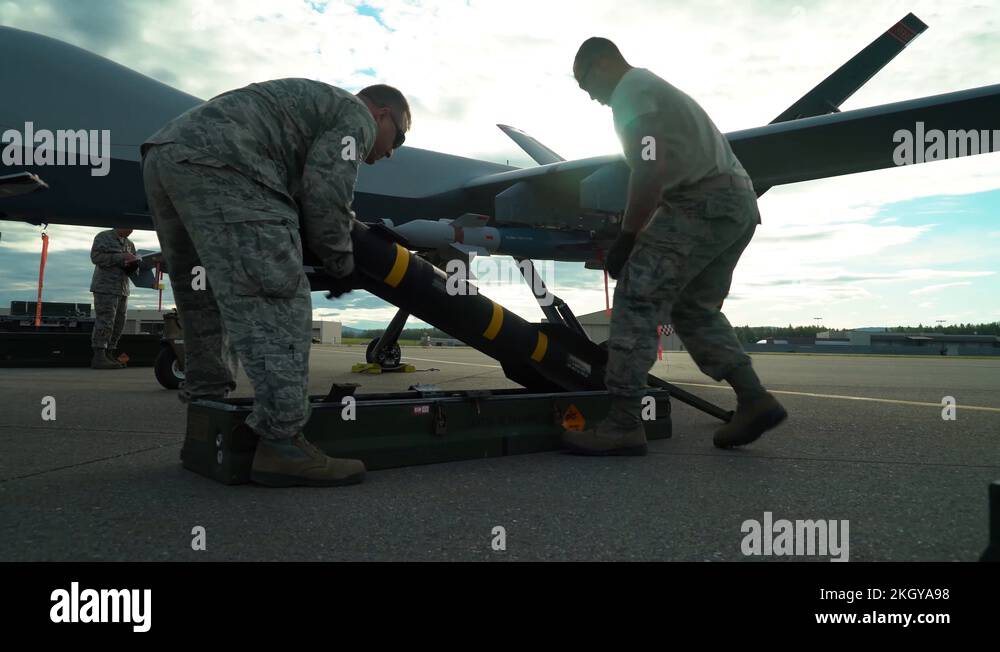 U.S. Air Force weapons specialists lifting munitions out of box for MQ ...