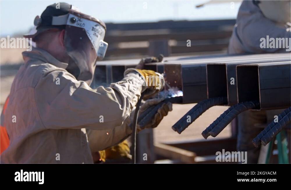Contractor welding reinforcing bar onto panel for new Mexican border ...