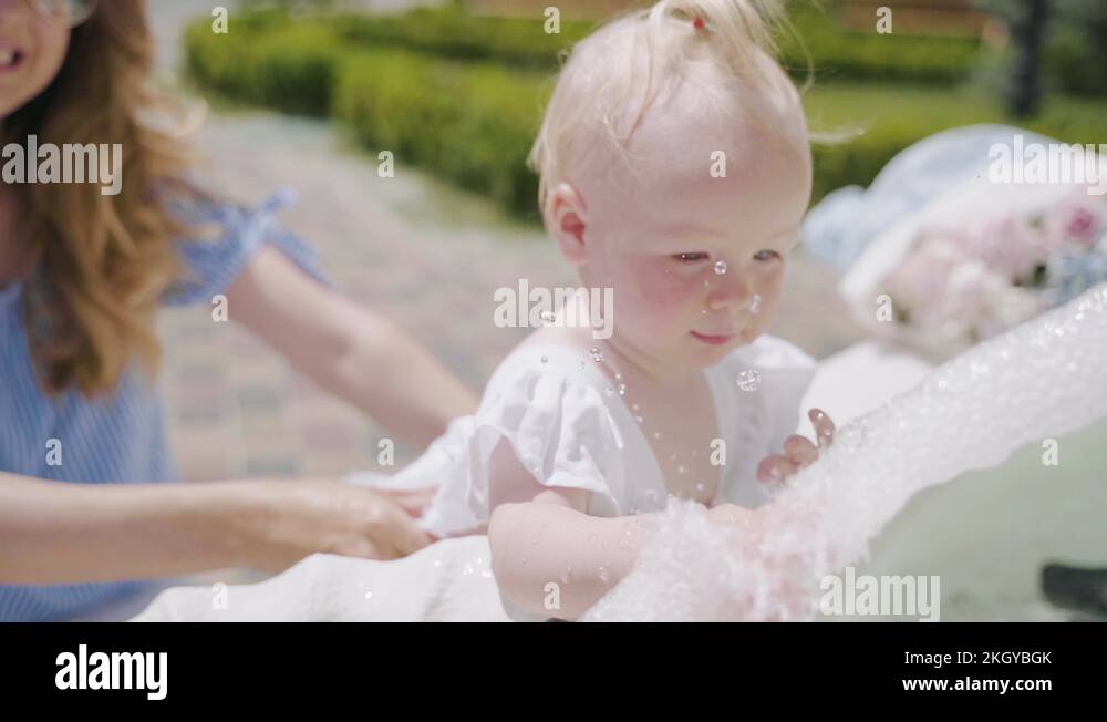 A close-up plan of a little girl playing with a water flow of the ...