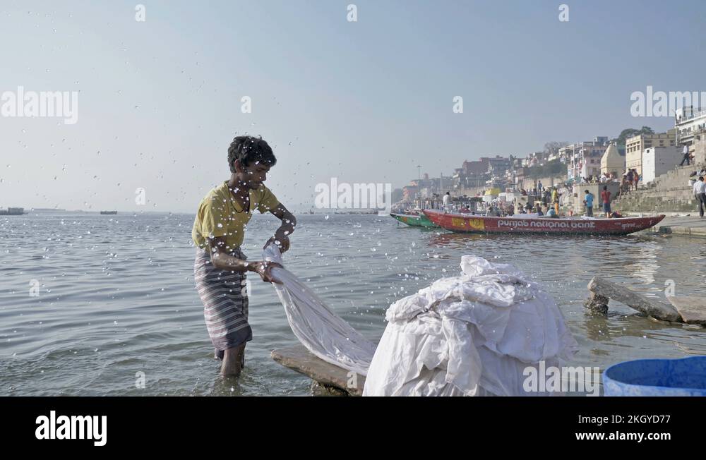 Indian man washing clothes on the banks of the Ganges in Varanasi ...