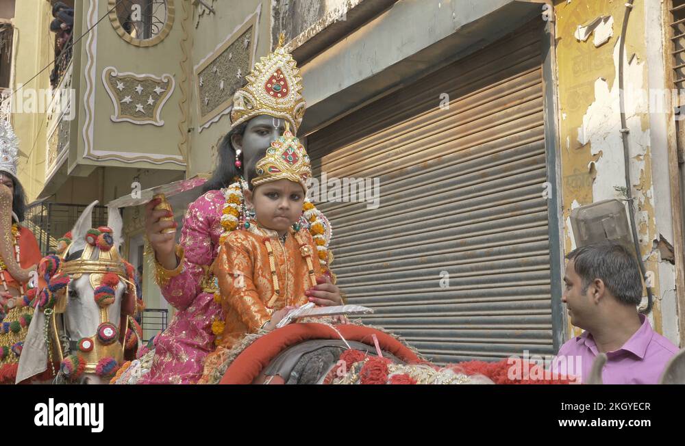 A small boy dressed as Lord Krishna with a small girl sitting on a ...