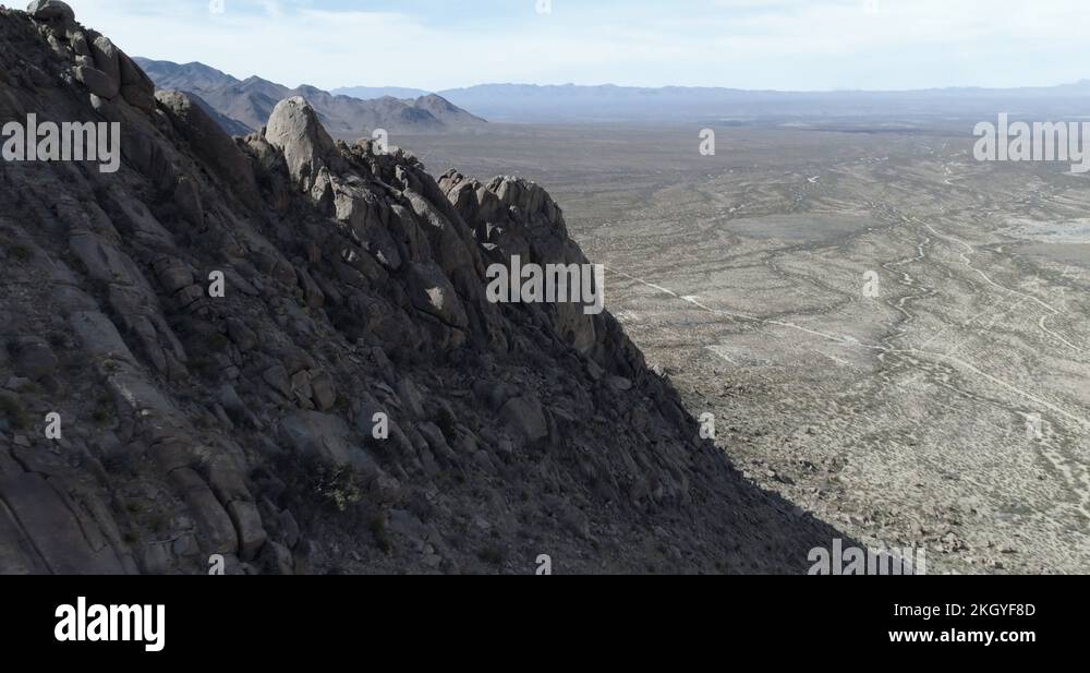 Cinematic pan around rocky outcrop reveals large mountain range drone ...